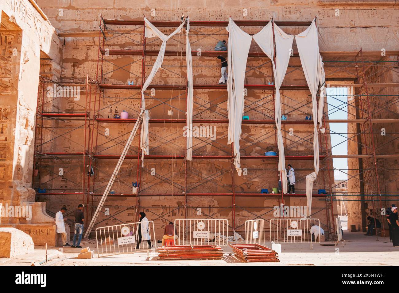workers in lab coats on scaffolding work to restore and preserve the ...