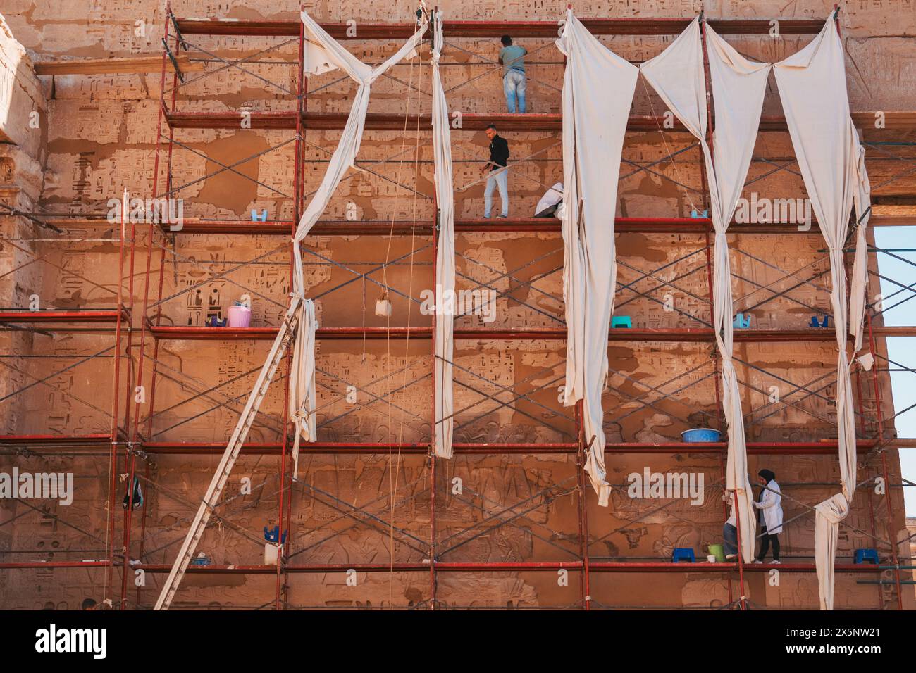 workers in lab coats on scaffolding work to restore and preserve the ...