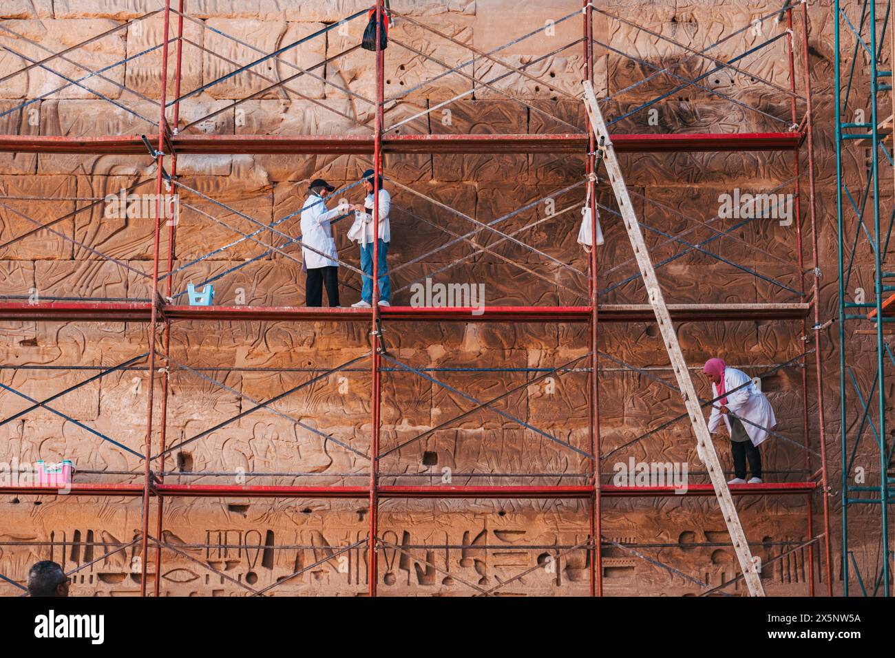 workers in lab coats on scaffolding work to restore and preserve the ...
