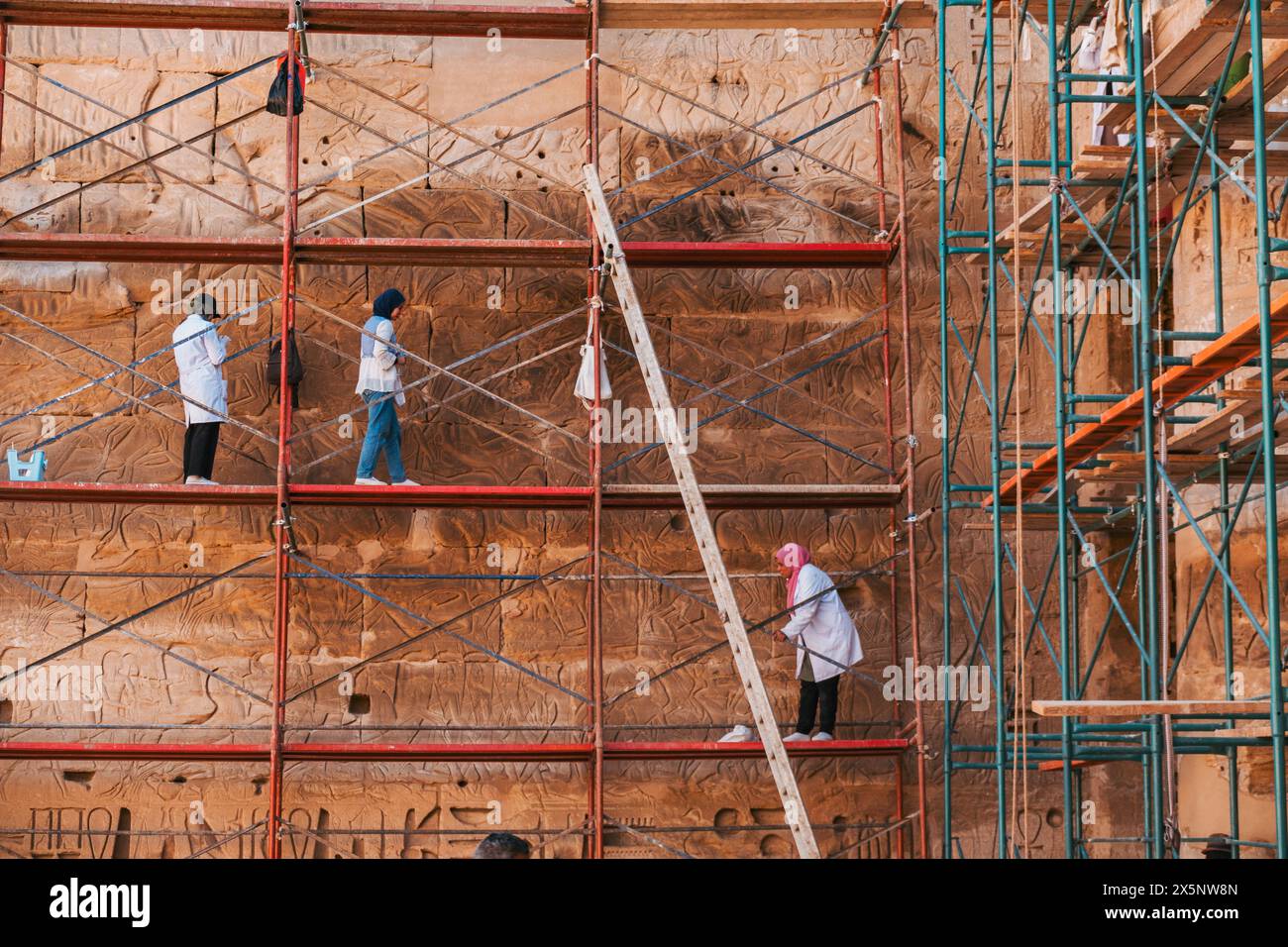 workers in lab coats on scaffolding work to restore and preserve the ...