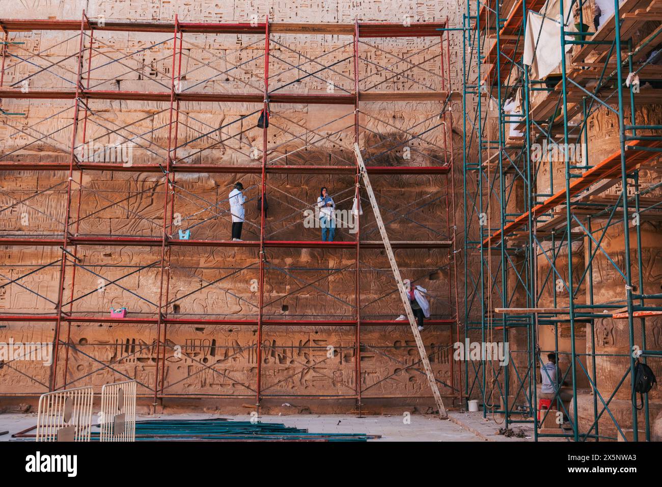 workers in lab coats on scaffolding work to restore and preserve the ...