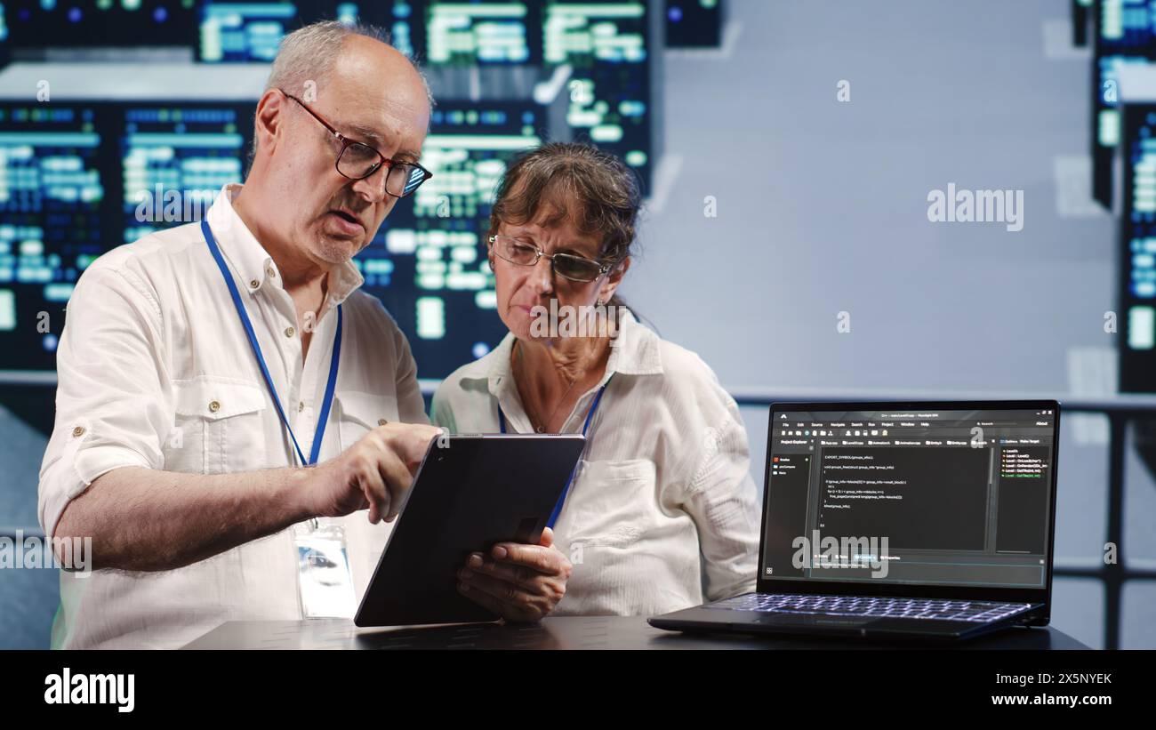 Data storage company executives solving tasks on tablet while running scripts on laptop terminal ...