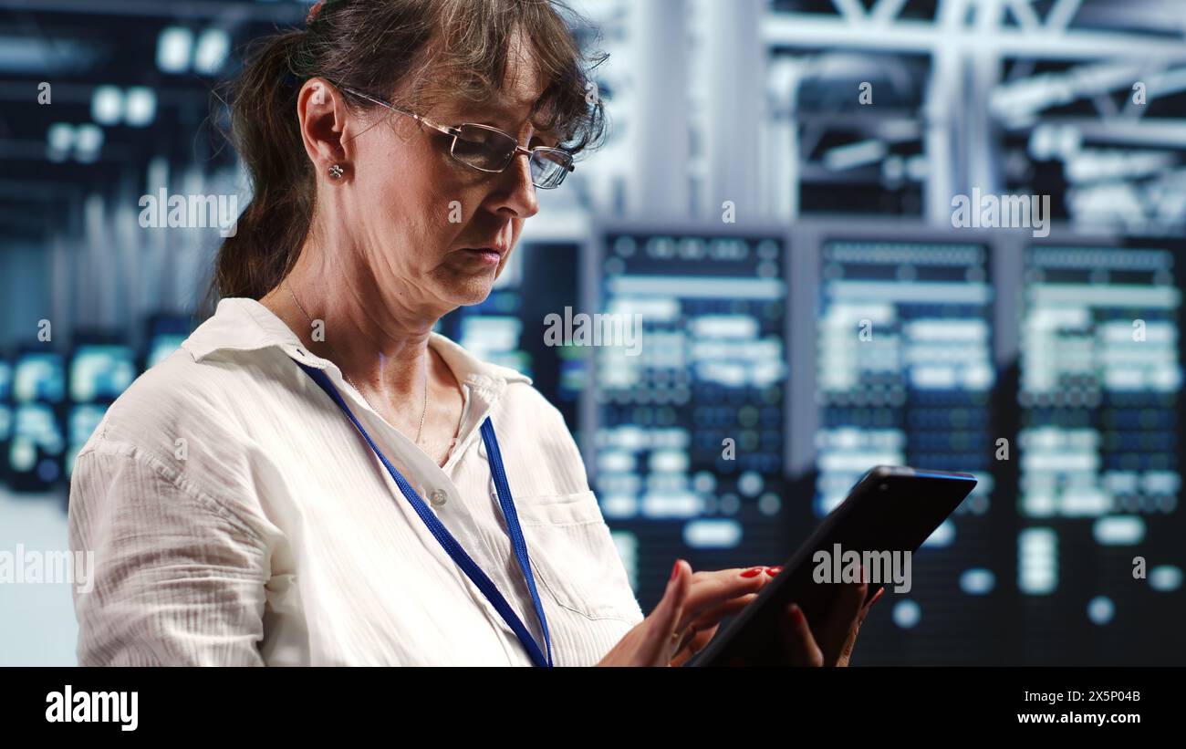 Aged technician working in data center housing GPU dedicated blade servers that can process ...