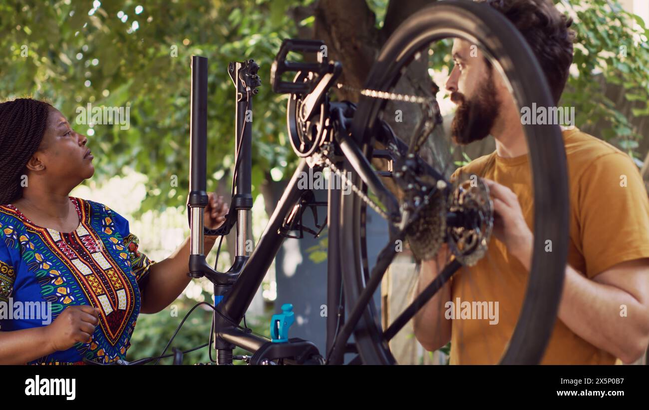 Fit and dedicated multiracial pair inspecting damaged bicycle for ...