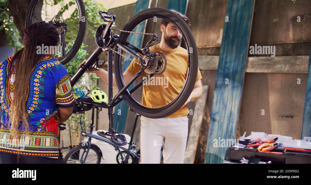 Young sports-loving multiracial couple repairing broken bicycle using ...