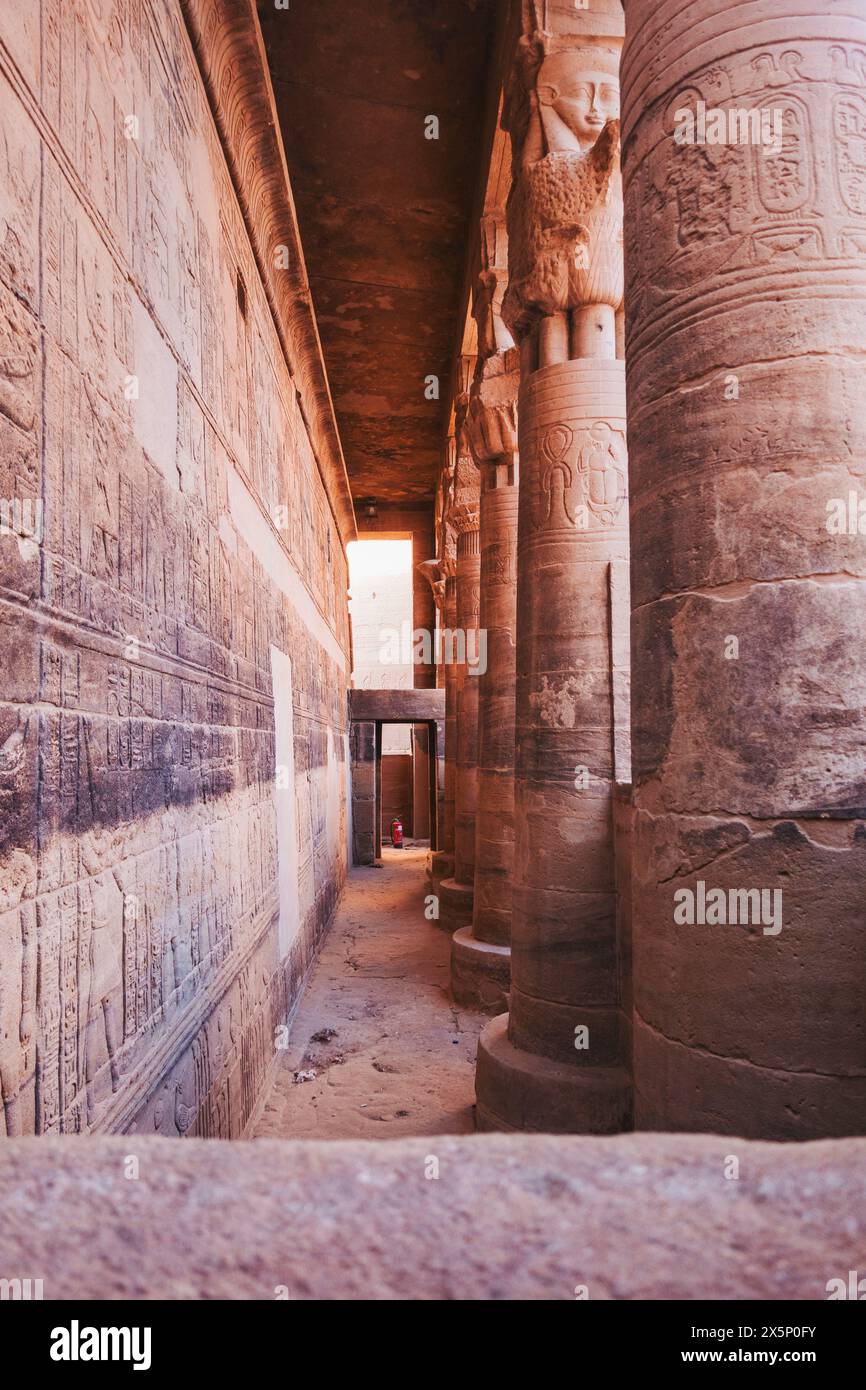 Ancient colonnade featuring carved walls and columns at Philae Temple ...