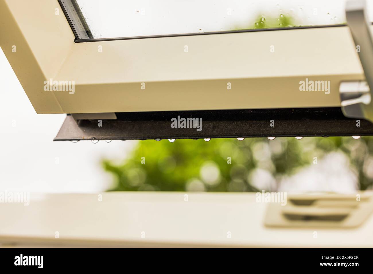 Close-up view of partially open attic window with raindrops streaming ...