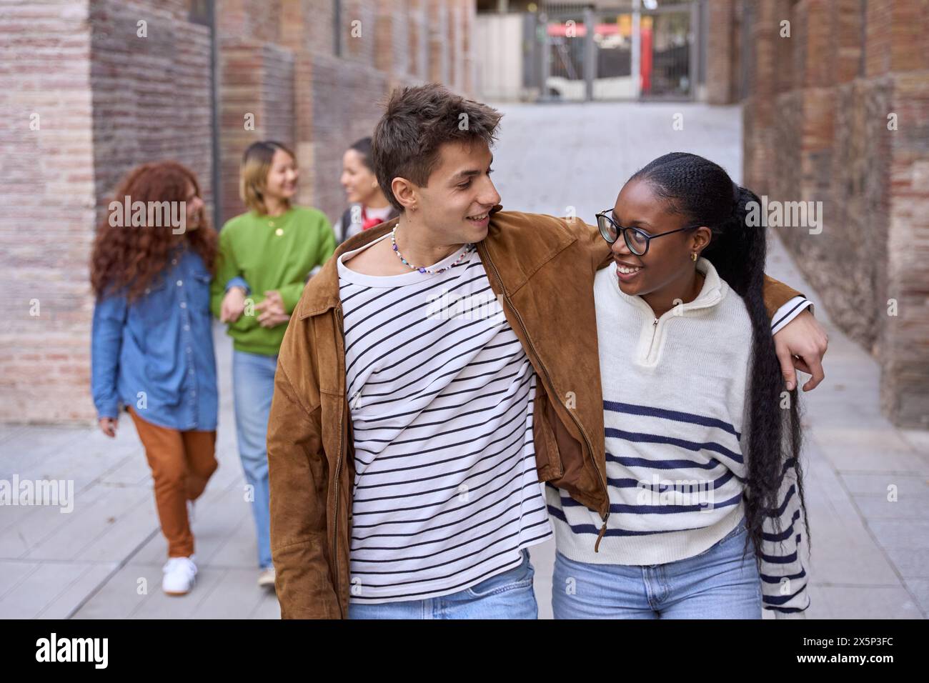 Couple of diverse genders happy students hugging strolling on the ...