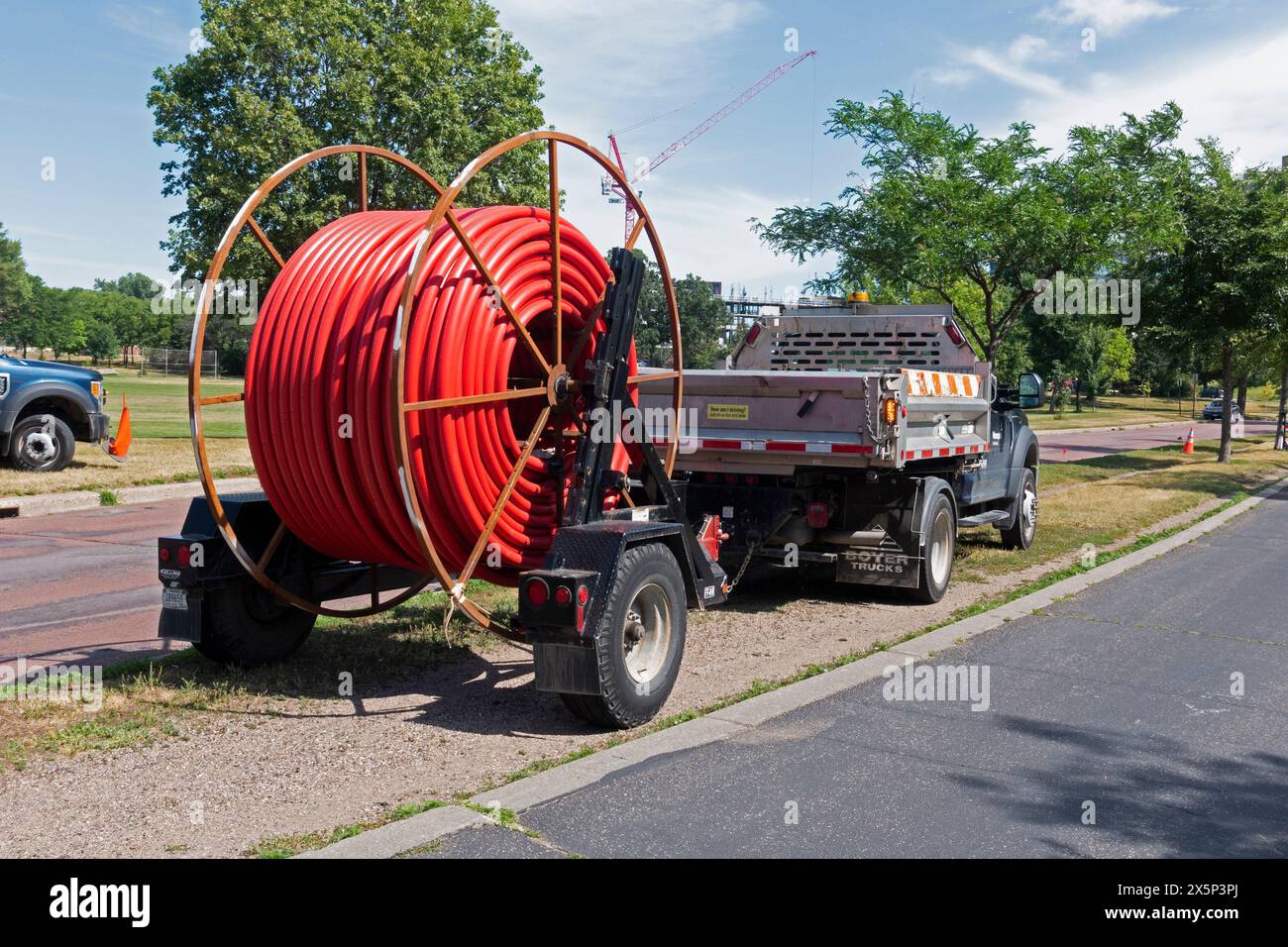Spool of orange conduit tubing pulled by truck to be buried in the ...
