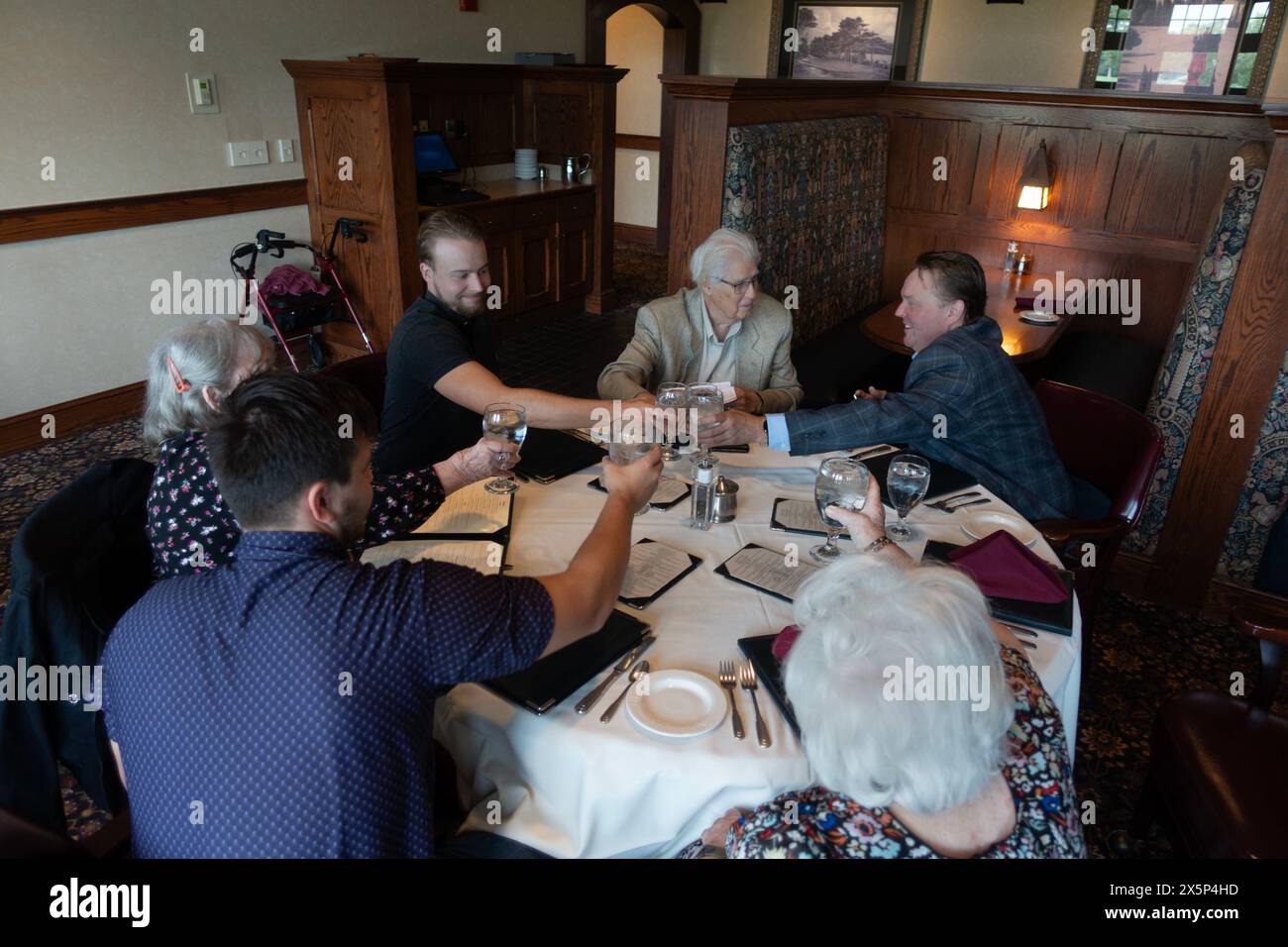 Celebratory dinner with three generations of family toasting with water ...