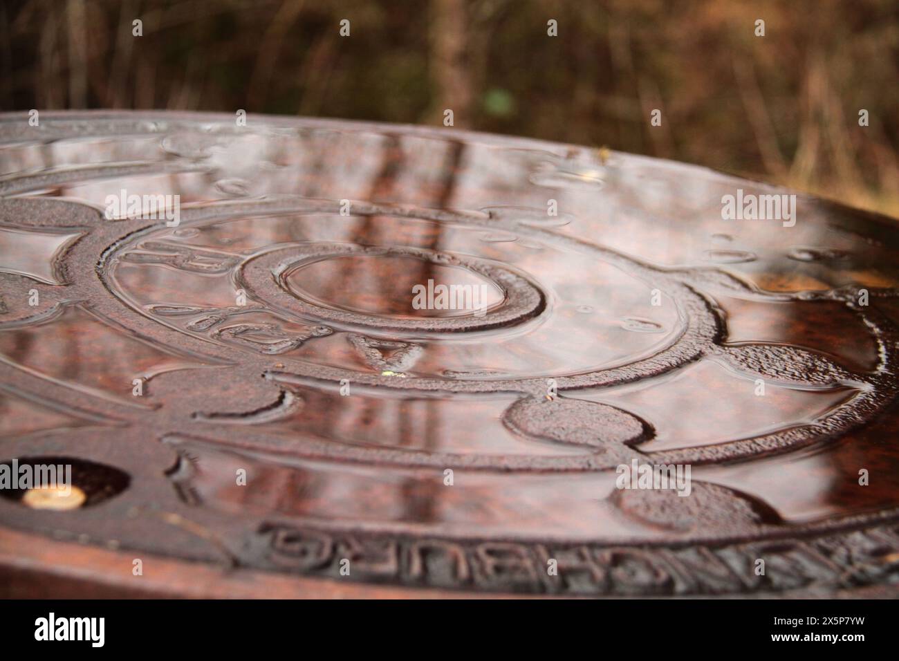 Close-up of a manhole cover with rain water on it Stock Photo - Alamy