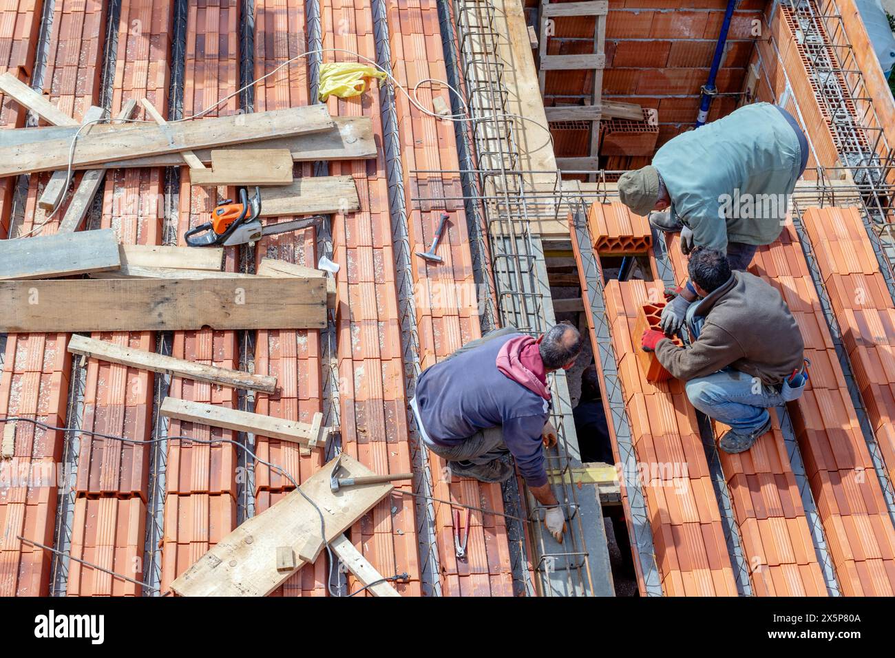 Construction workers prepare a steel mesh to reinforce a roof slab ...