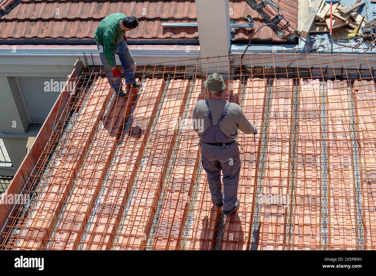 Construction workers prepare a steel mesh to reinforce a roof slab ...