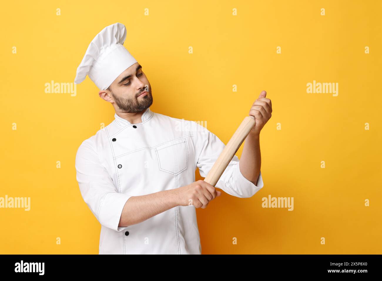 Professional chef with rolling pin on yellow background Stock Photo - Alamy