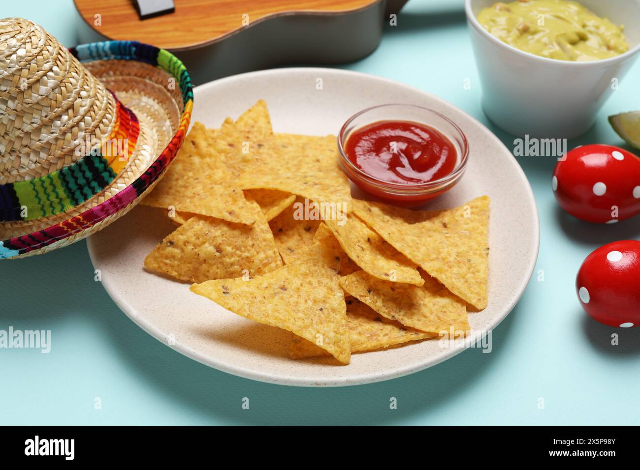 Nachos chips, sauce, Mexican sombrero hat, maracas and guacamole on ...