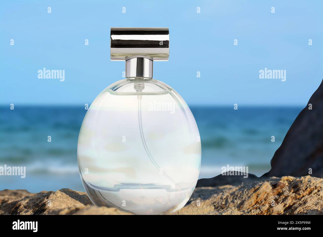 Bottle of aquatic perfume on rock near ocean. Fresh sea breeze scent ...