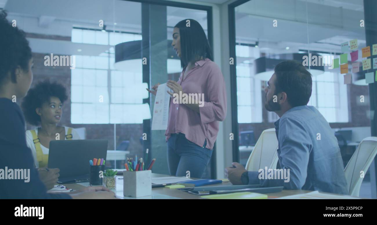 Diverse group of friends discussing in office, holding business papers ...