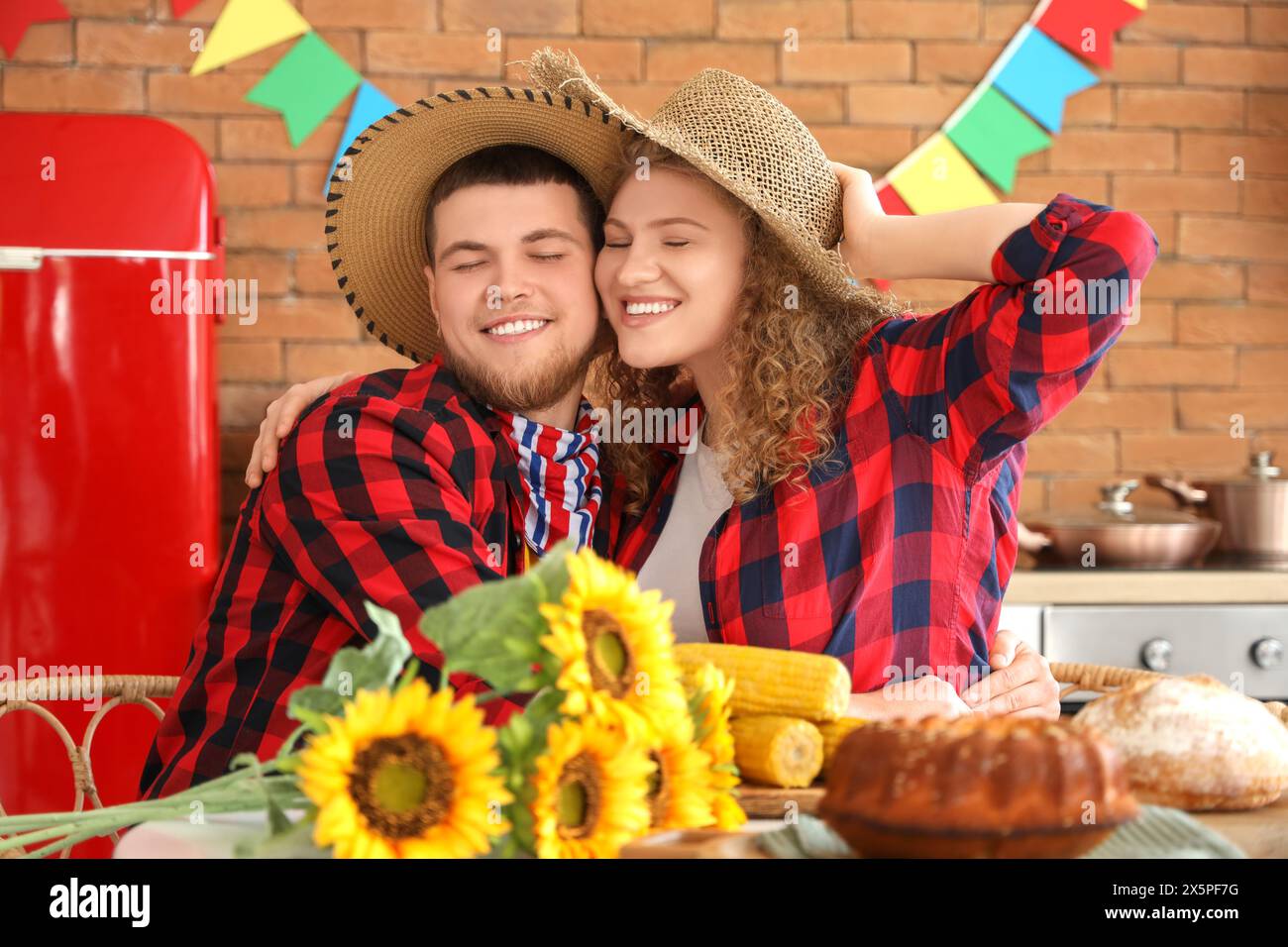Happy young couple sitting at table with sunflowers and peanuts in ...