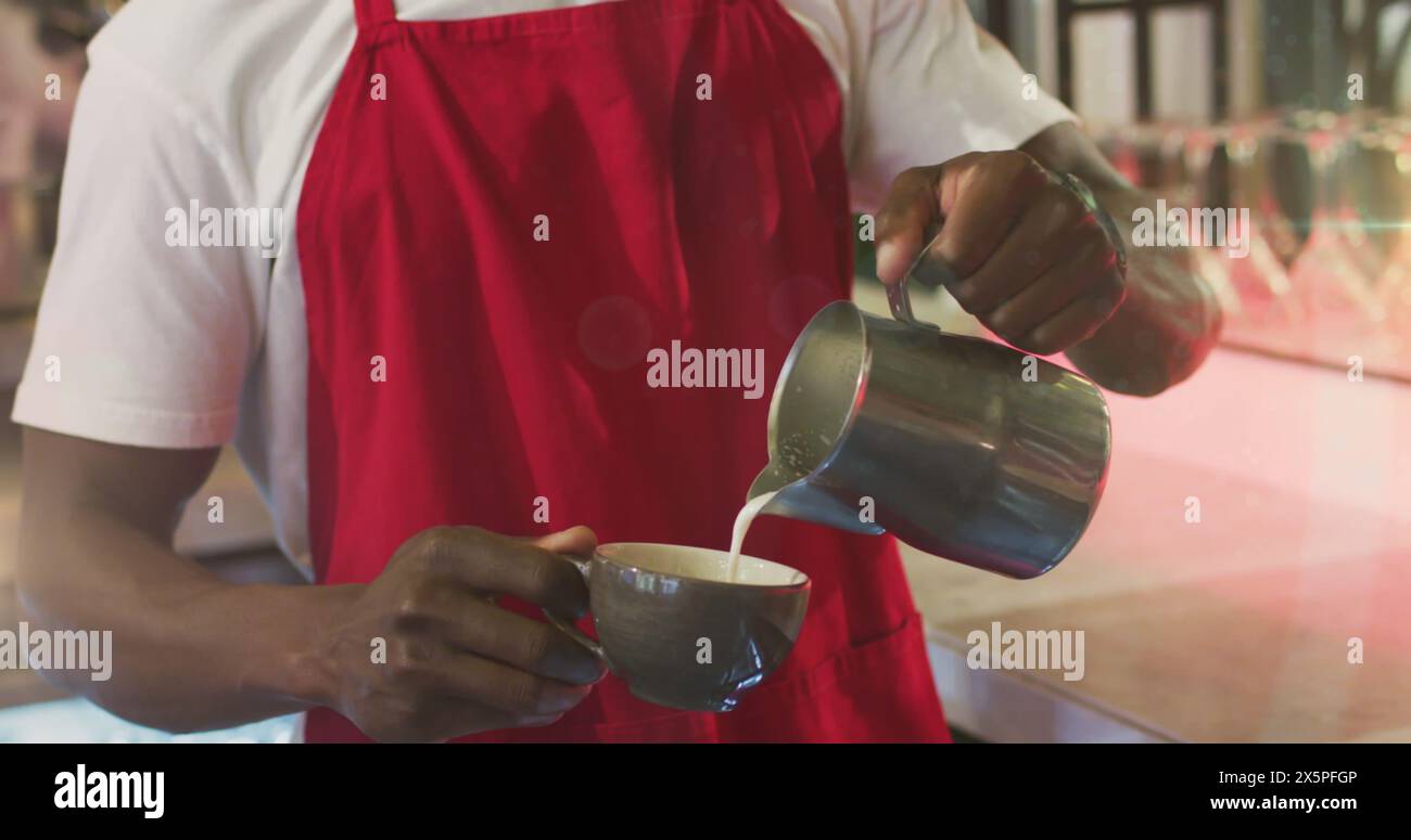 A young African American professional pouring milk into coffee cup ...