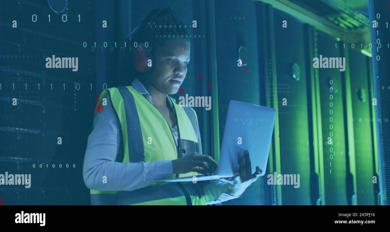 Image Of Computer Language African American Female Engineer Using Laptop In Server Room Stock