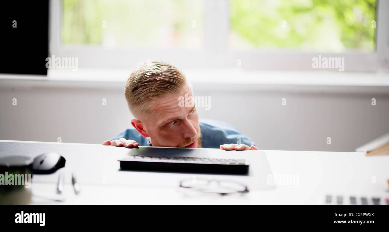 Scared Man Hiding Behind Office Desk In Room Stock Photo - Alamy