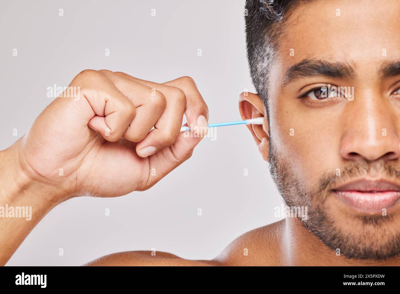 Indian man, studio and portrait with cotton for cleaning ear or self ...
