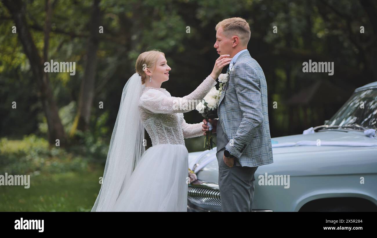 The bride and groom linger by the retro car on their wedding day Stock ...