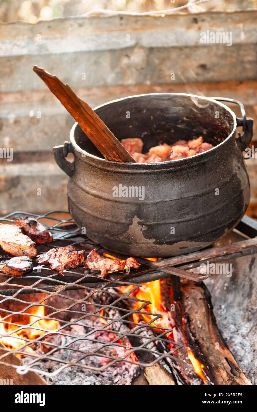 african cooking , meat on the barbeque, large black cauldron pot ...