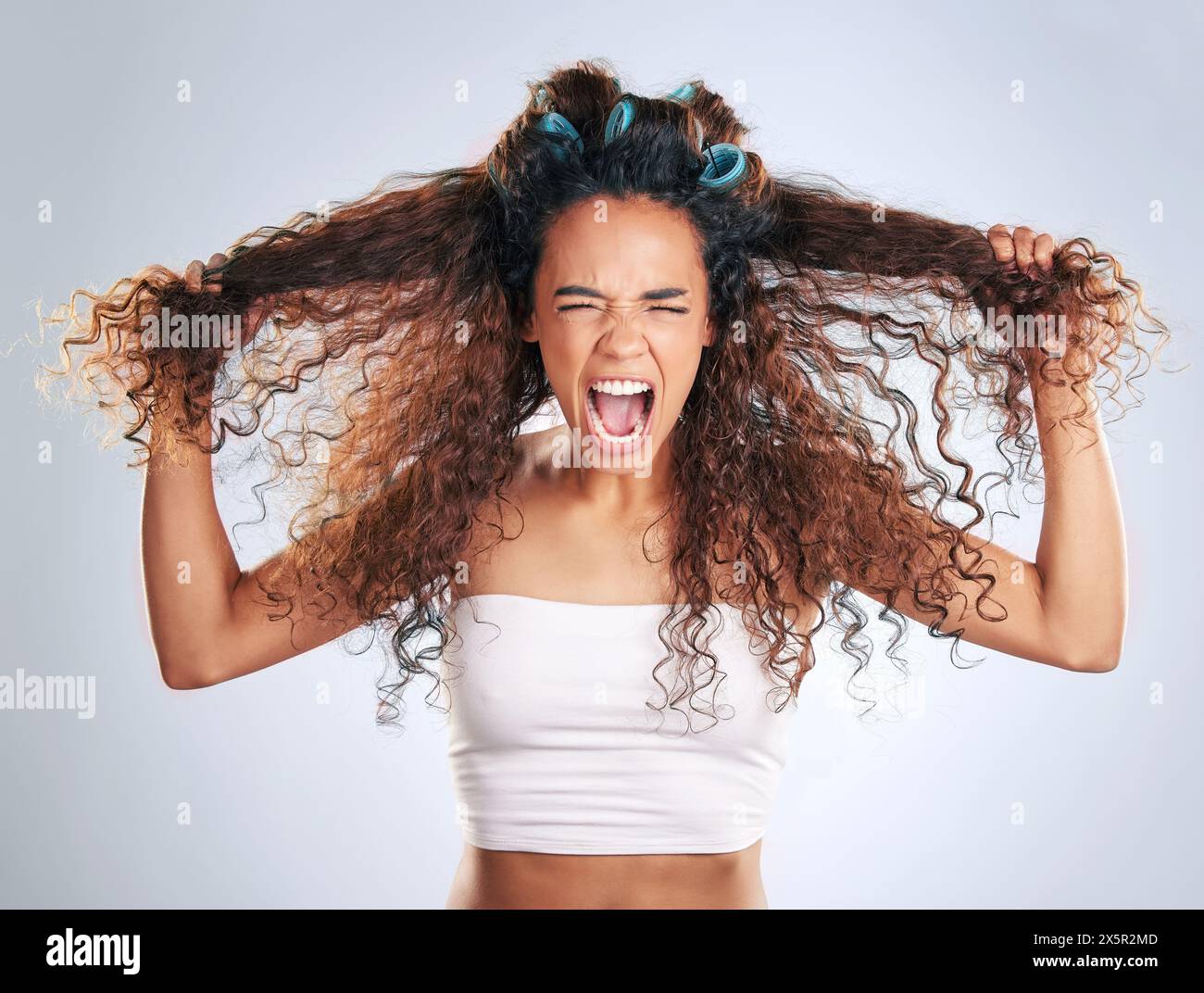 Angry, beauty and hair with woman screaming in studio on gray ...