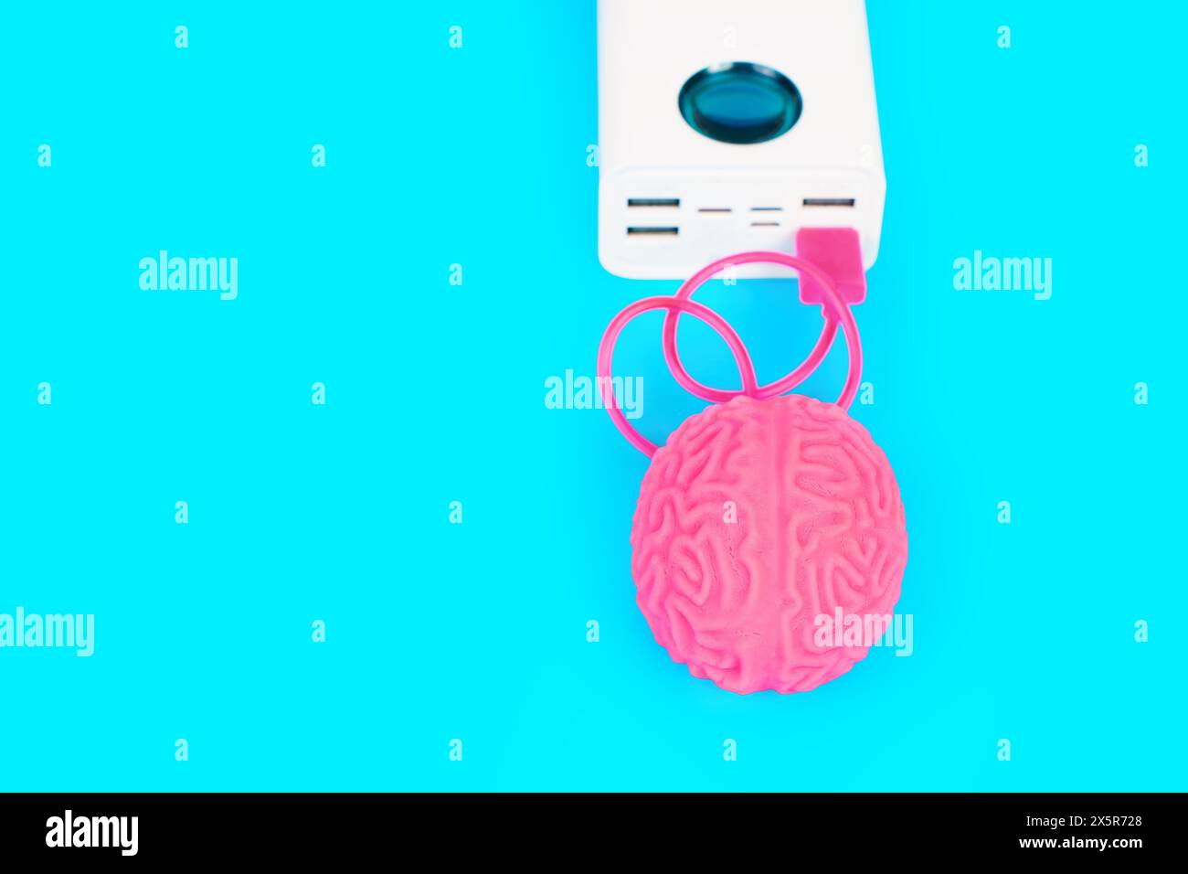 Soft human brain model connected to a white power bank isolated on blue ...