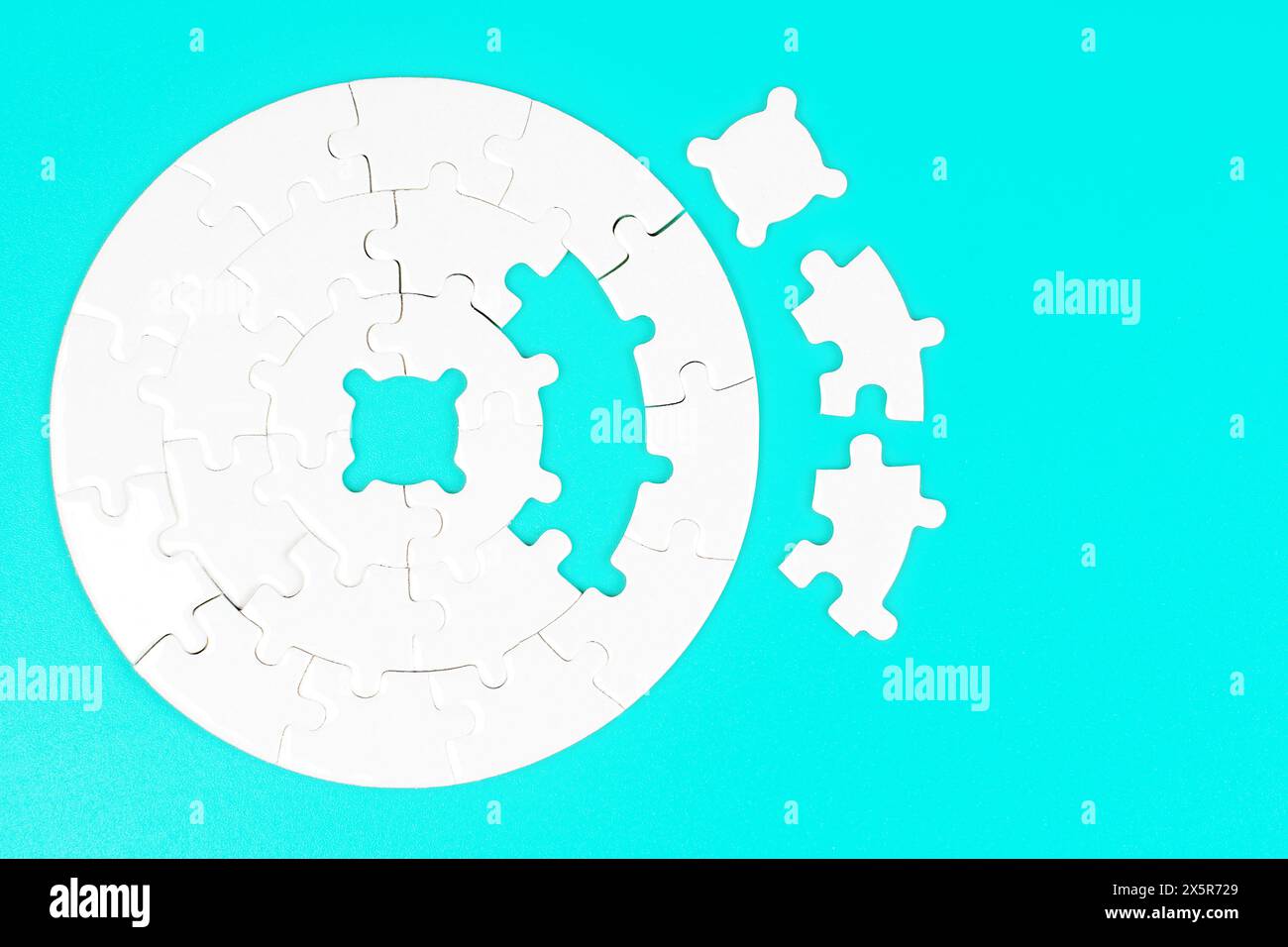 Top view of an incomplete white circular jigsaw puzzle with three final ...