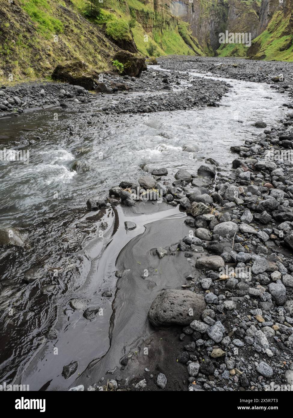A wild river flows through a rocky gorge of lava rock surrounded by ...