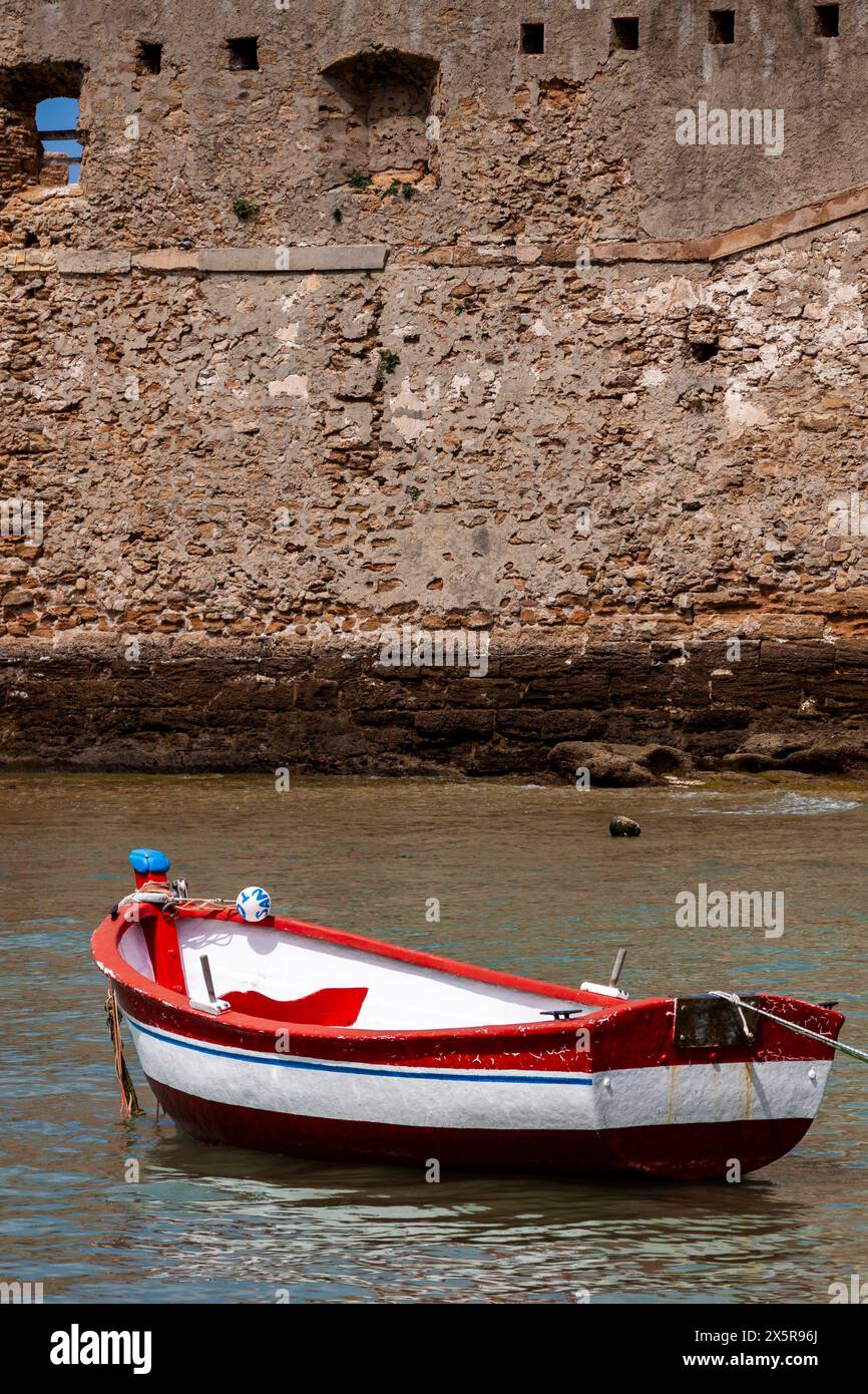 Small fishing boat anchored in front of the historic city wall in Cadiz ...