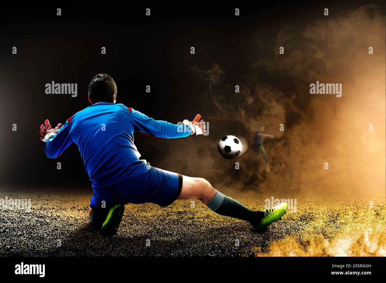 Portrait of a male goalkeeper trying to stop the ball on the pitch with ...