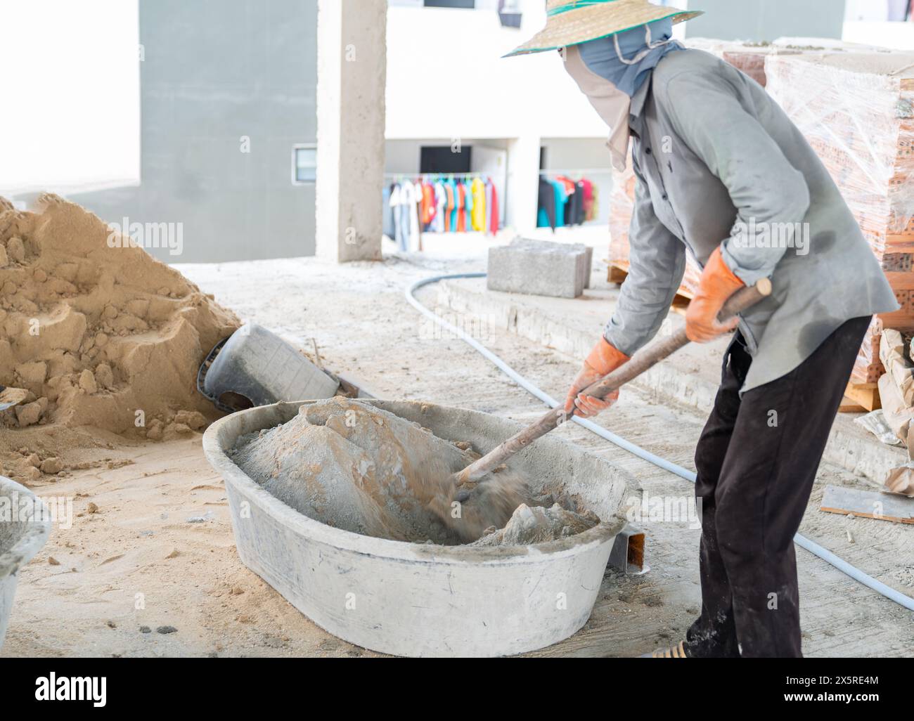 Worker using hoe to mixing sand and cement manually at construction ...