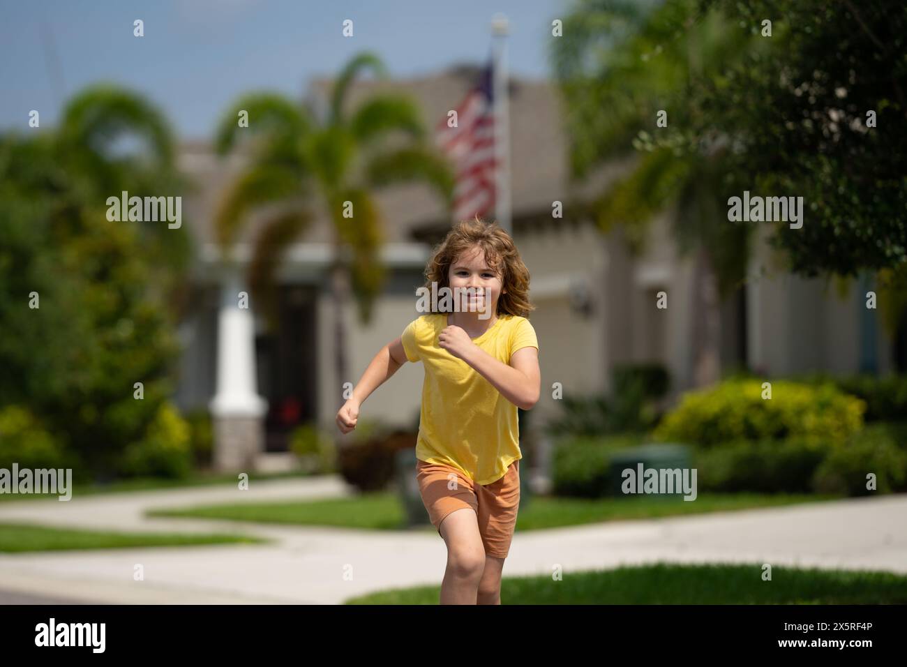 Cute kid boy running across american neighborhood street. Summer ...