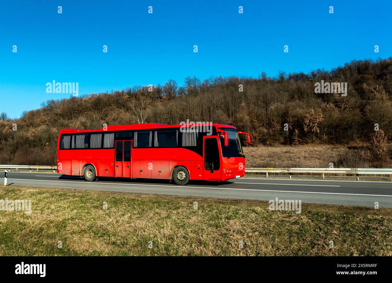 Red Modern comfortable tourist bus driving through highway at bright ...