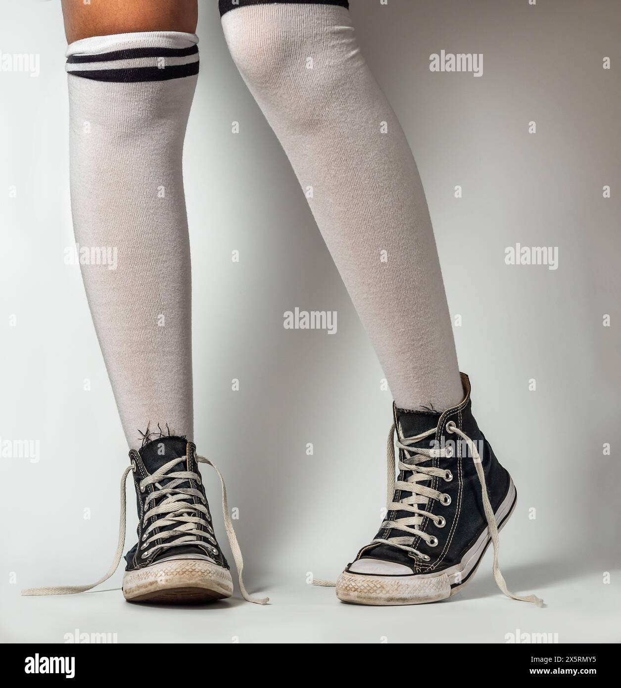 Old blue sneakers hipster style on girl legs in over the knee socks, on ...