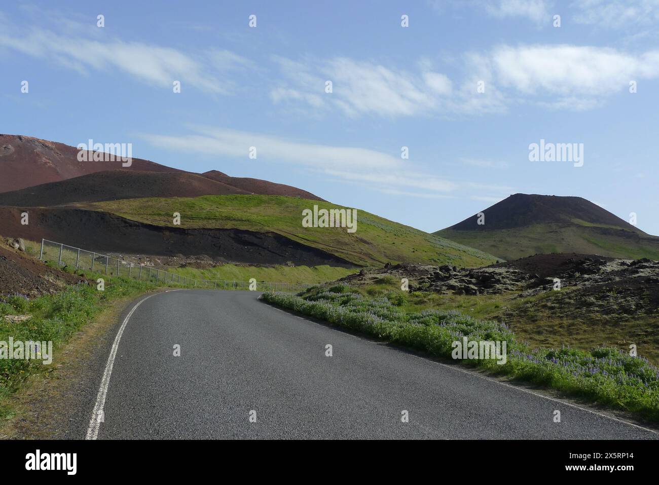 An asphalt road passes through the black lava flow left behind by the ...