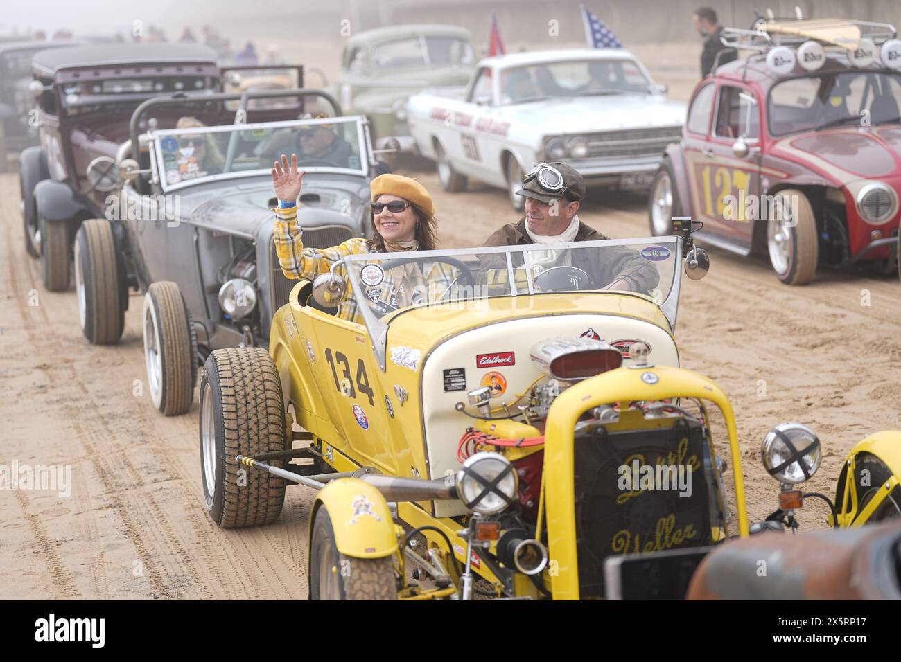 A procession of American and vintage style hot-rod vehicles on the ...
