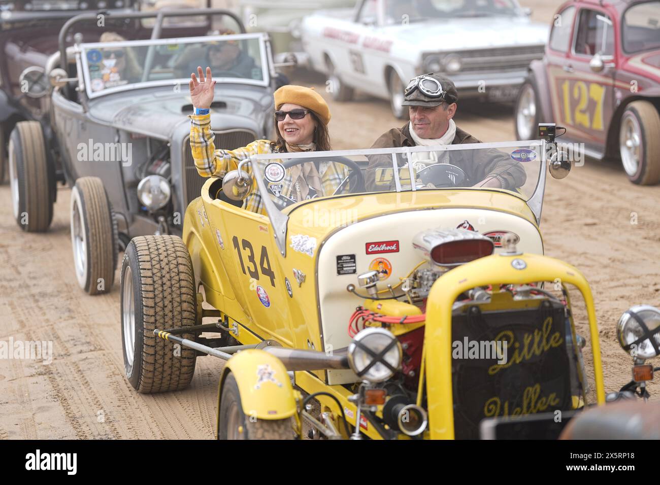 A procession of American and vintage style hot-rod vehicles on the ...