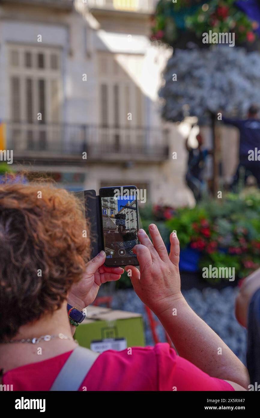 A woman is taking a picture of a flower structure with a phone. Temps ...