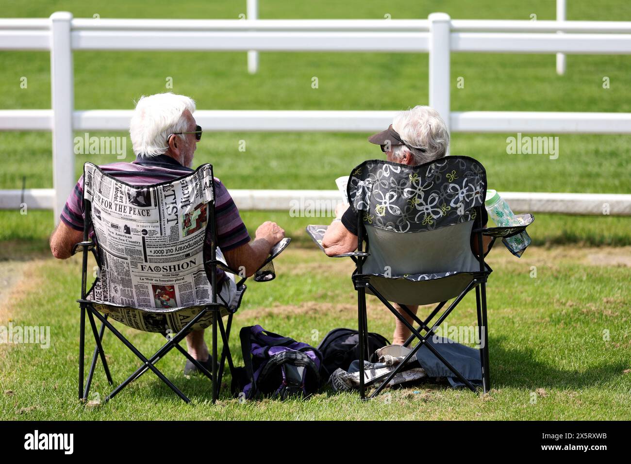 Racegoers sit next to the track as they wait for the first race of the ...