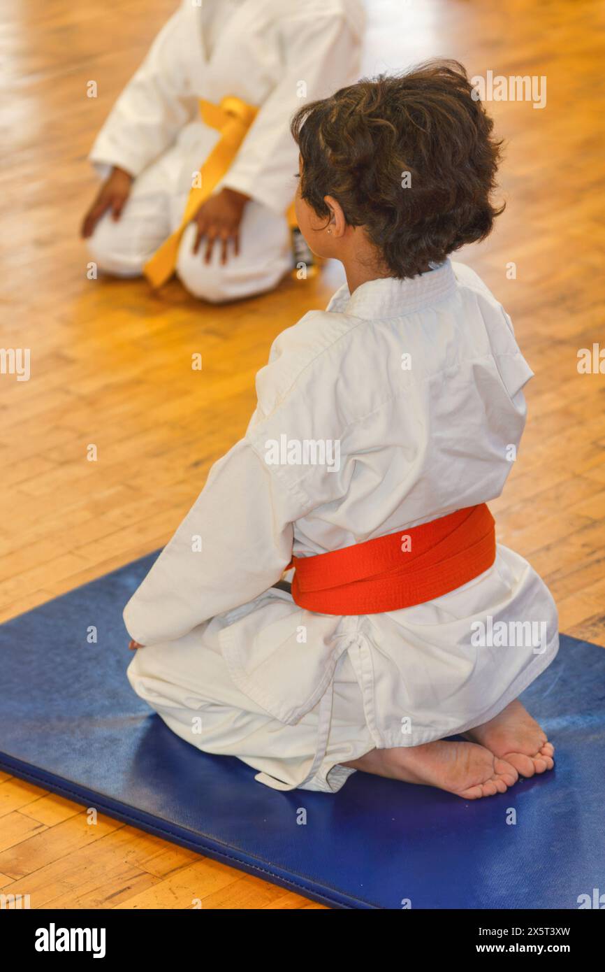girl practicing karate kneeling on a blue mat in the dojo Stock Photo ...