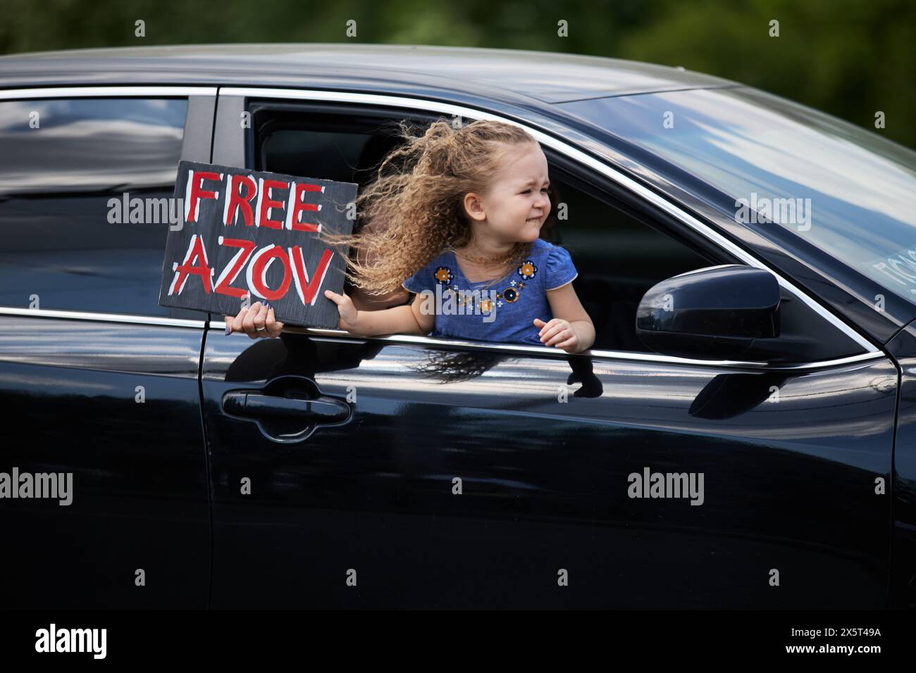 Cute Ukrainian girl rides in a car with a sign "Free Azov" in hands ...