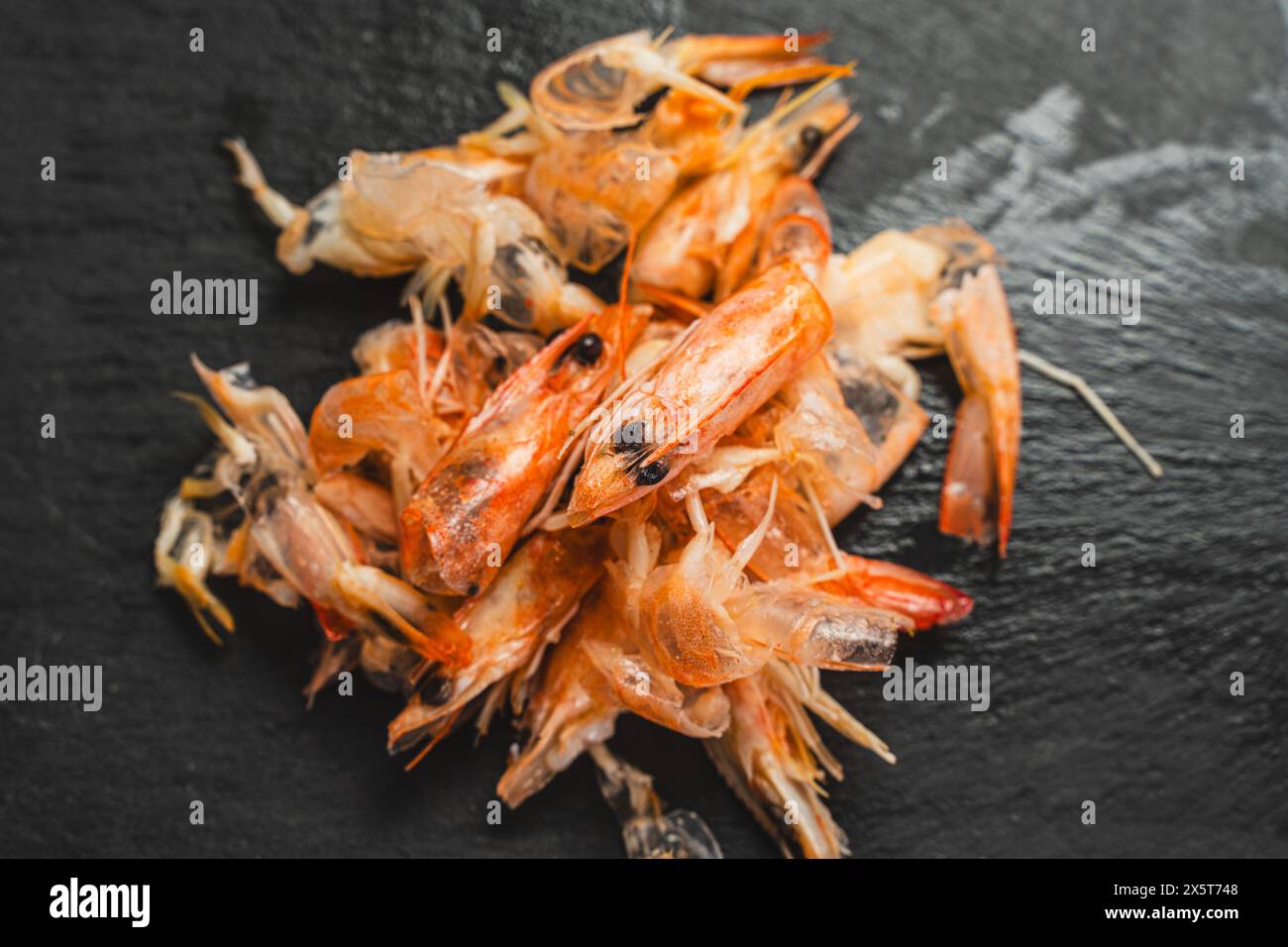 Cleaning shrimp in a bowl Remains of shrimp armor on a black plate ...