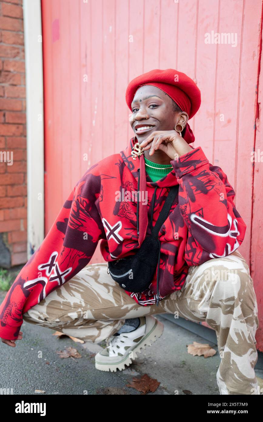 Portrait of crouching young woman wearing red Stock Photo - Alamy