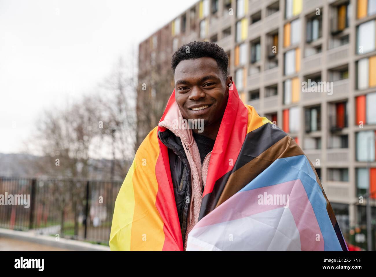 Portrait of young man wrapped in progress pride flag Stock Photo - Alamy