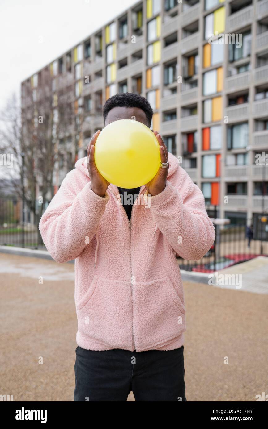 Young man holding balloon in front of face Stock Photo - Alamy