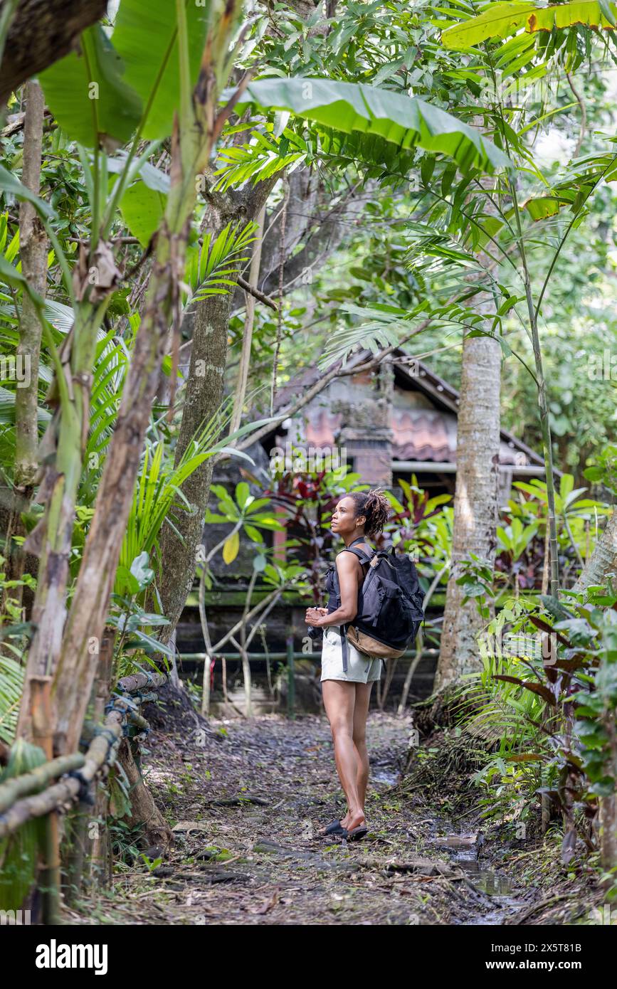 Indonesia, Bali, Female tourist looking at exotic trees in rainforest ...